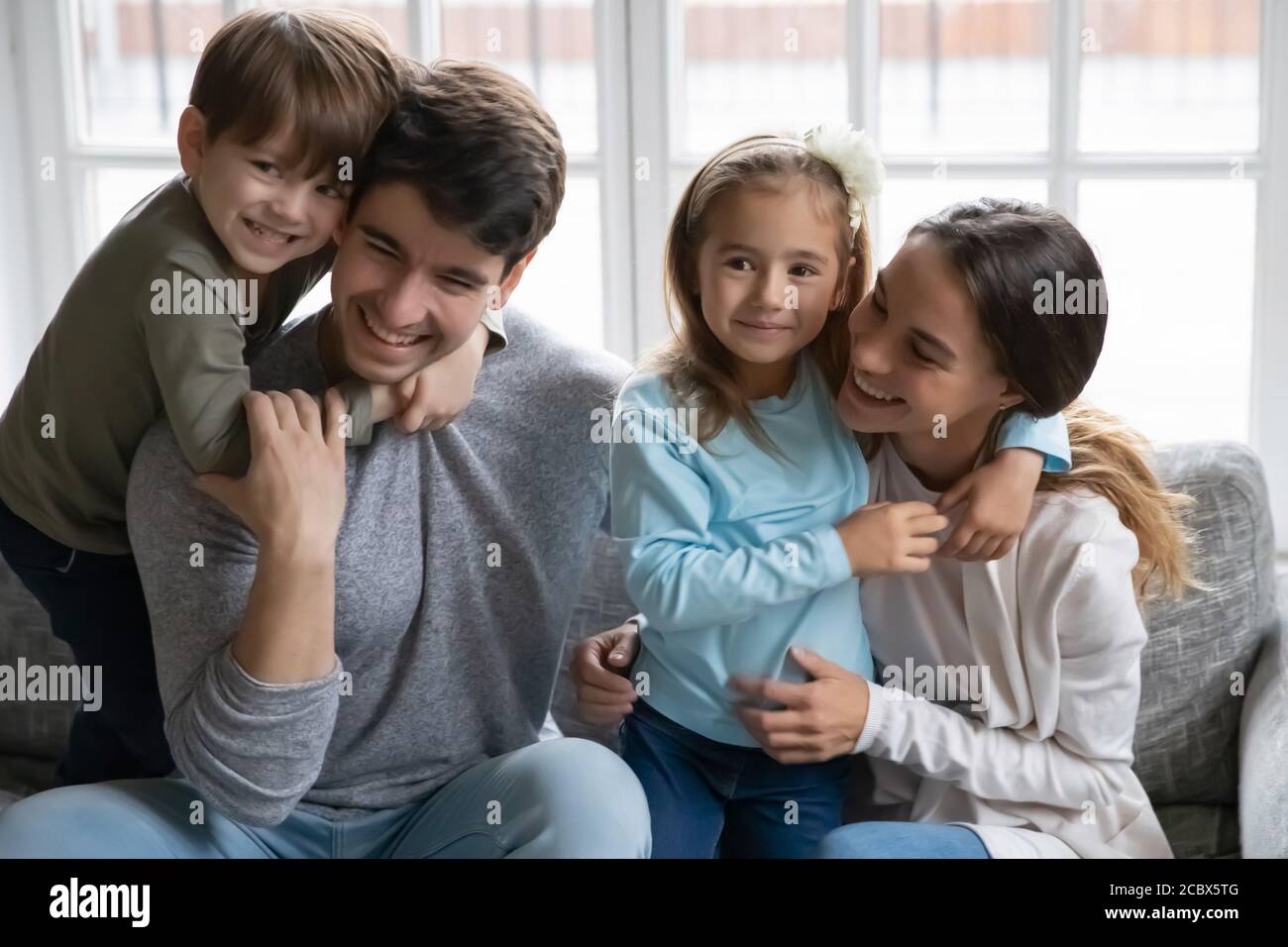 Happy adorable small children cuddling affectionate loving parents ...