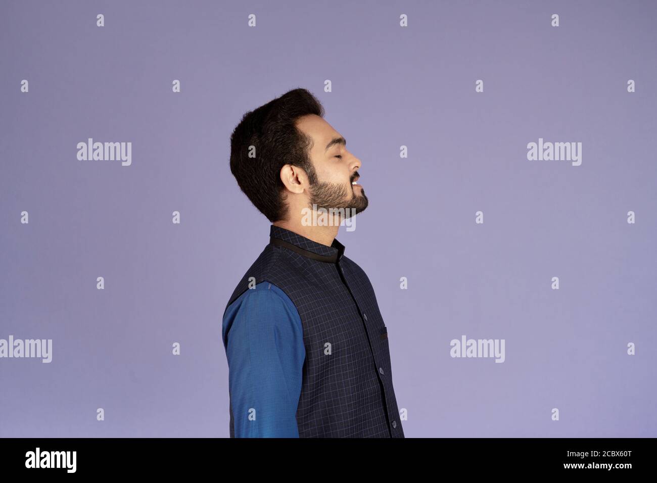 Side view of peaceful Indian man with closed eyes relaxing on lilac ...