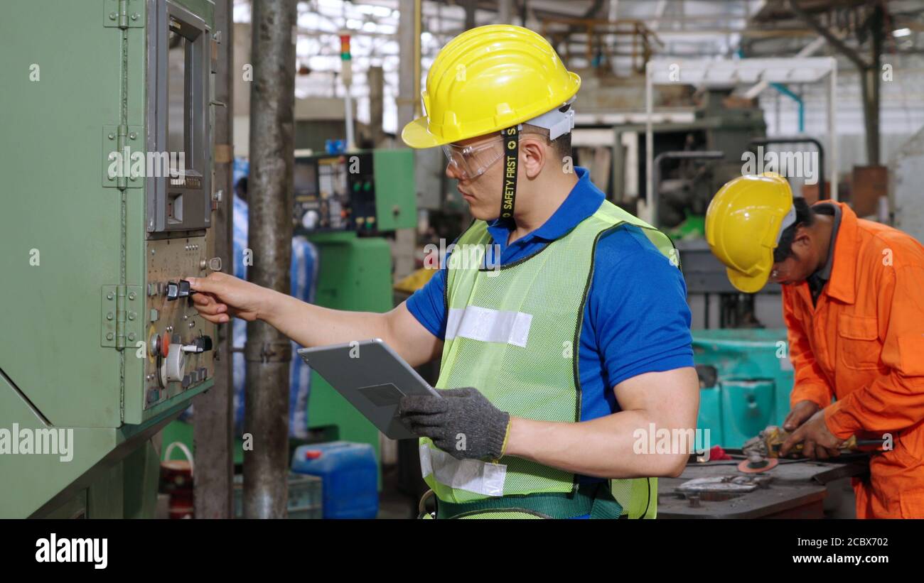 Smart factory worker using machine in factory workshop Stock Photo - Alamy
