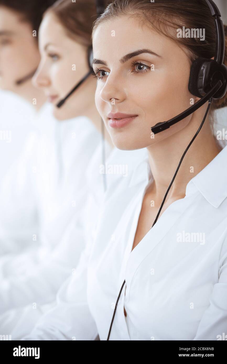 Call center. Beautiful young woman using headset and computer to help ...