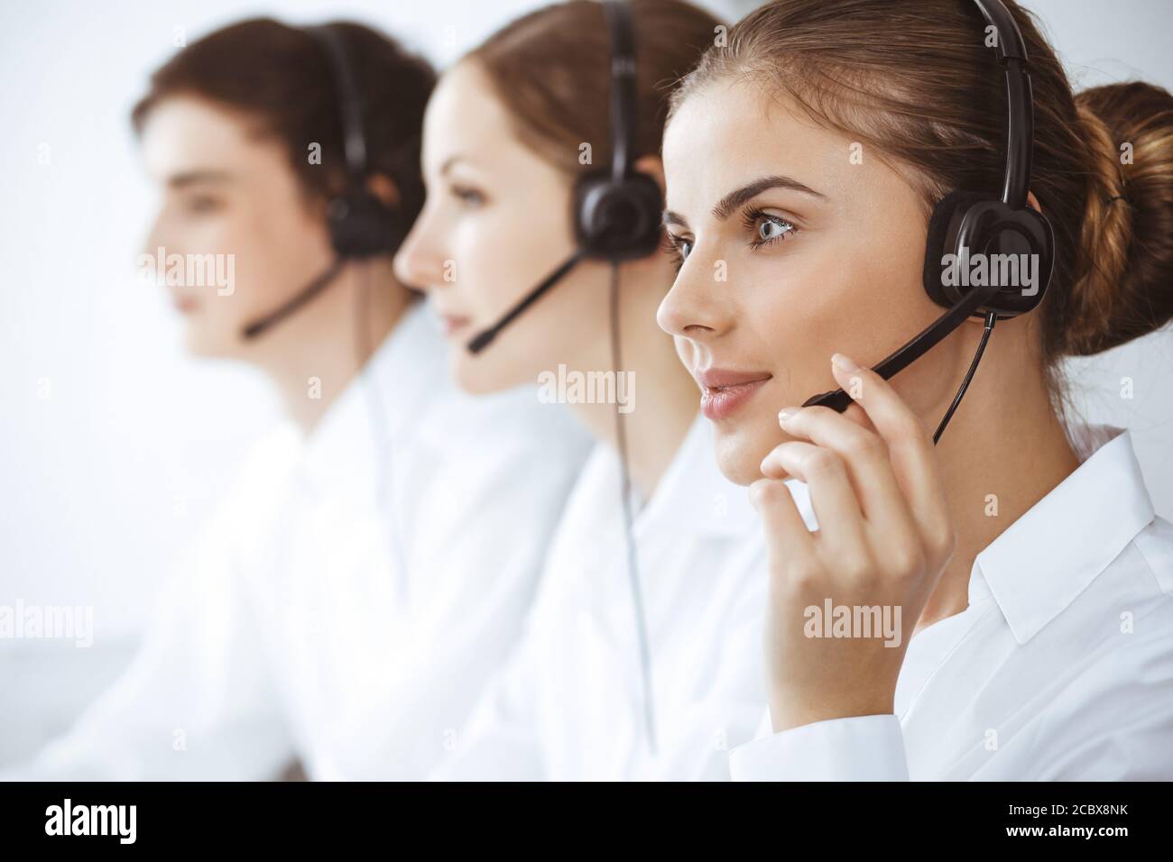 Call center. Beautiful young woman using headset and computer to help ...