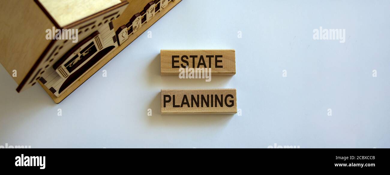 Wooden blocks form the words 'estate planning' near miniature house ...