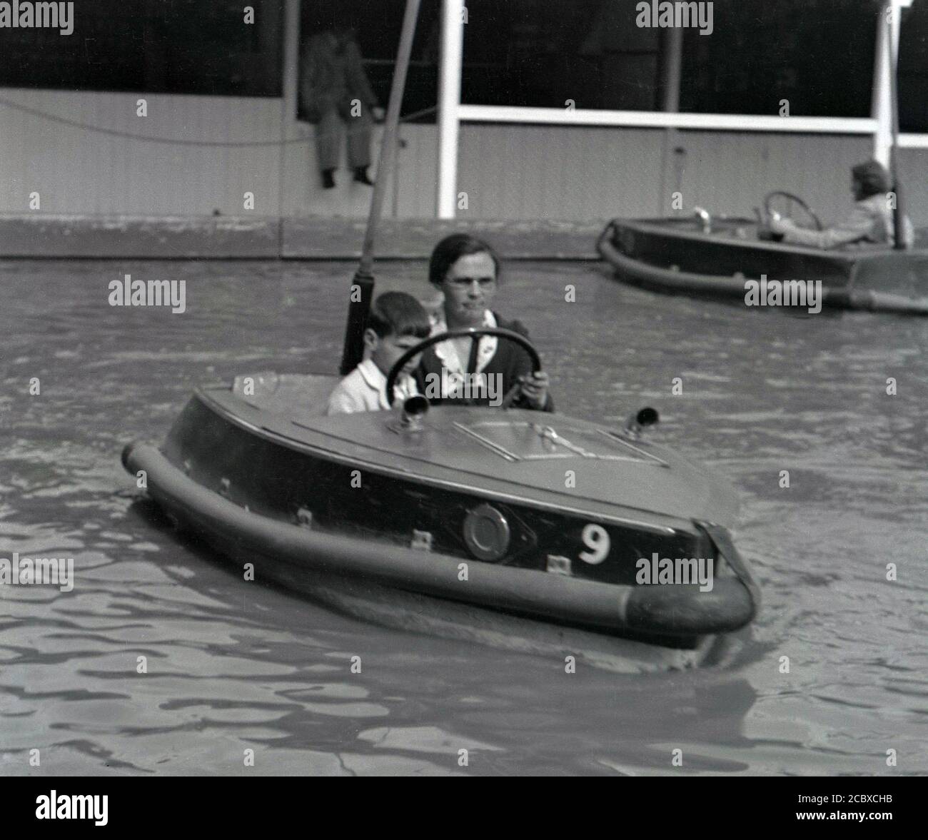 1940s, historical, a mother and young son riding in a water dodgem or ...