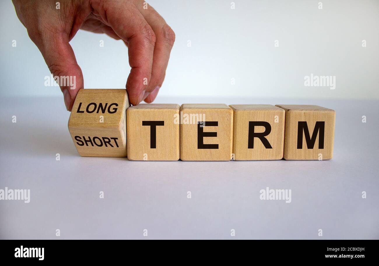 Hand turns a cubes and changes the expression 'SHORT TERM' to 'LONG ...