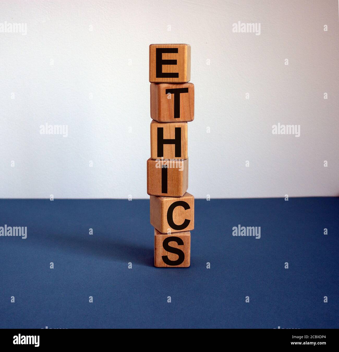 Wooden cubes form the word 'ethics' on blue table. Beautiful white ...
