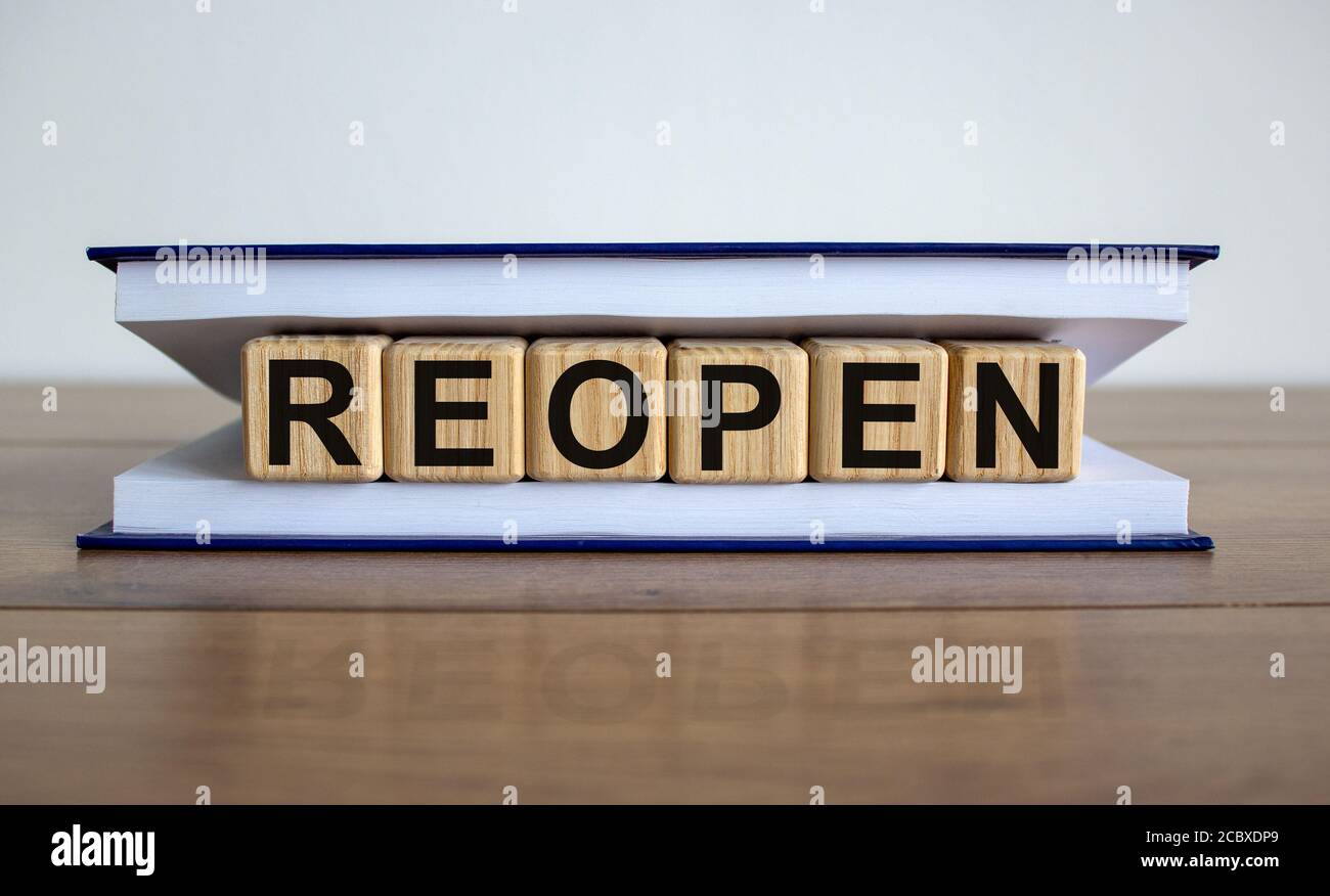 Concept word 'reopen' on wooden cubes between pages of a book on a ...