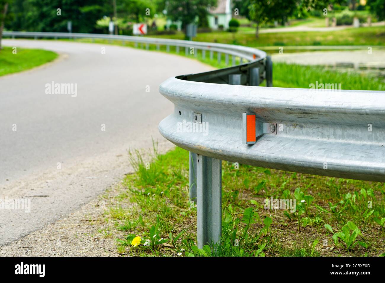 asphalt road bend with a metal protection barrier in the foreground ...
