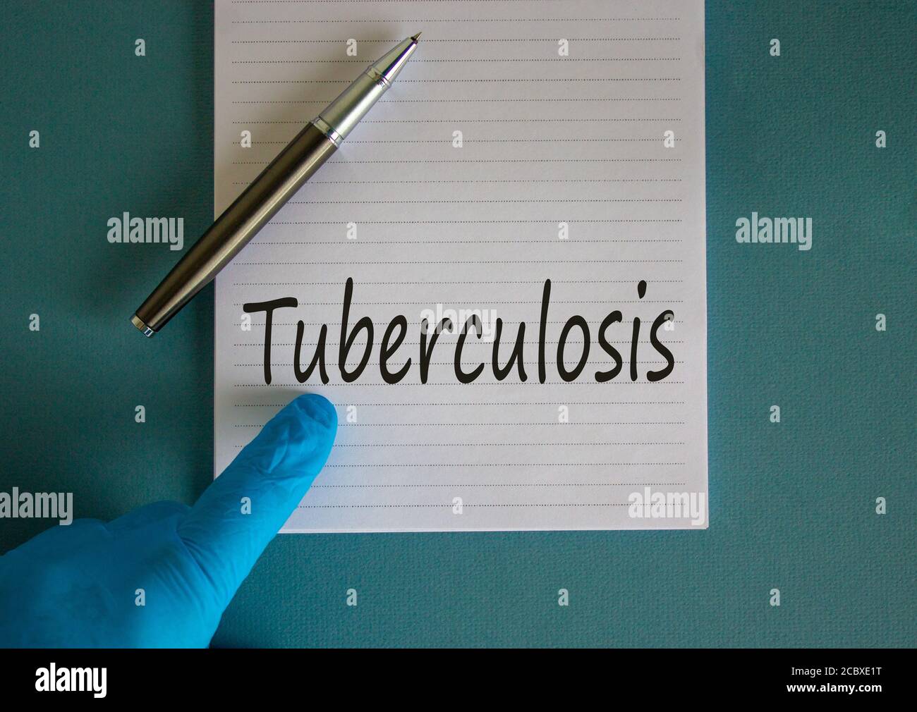 Hand in blue glove, pen, white note with word 'tuberculosis'. Medical ...