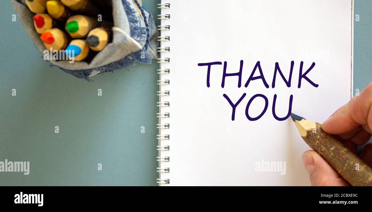 Hand writing 'thank you', isolated on blue background. Bag with pencils ...