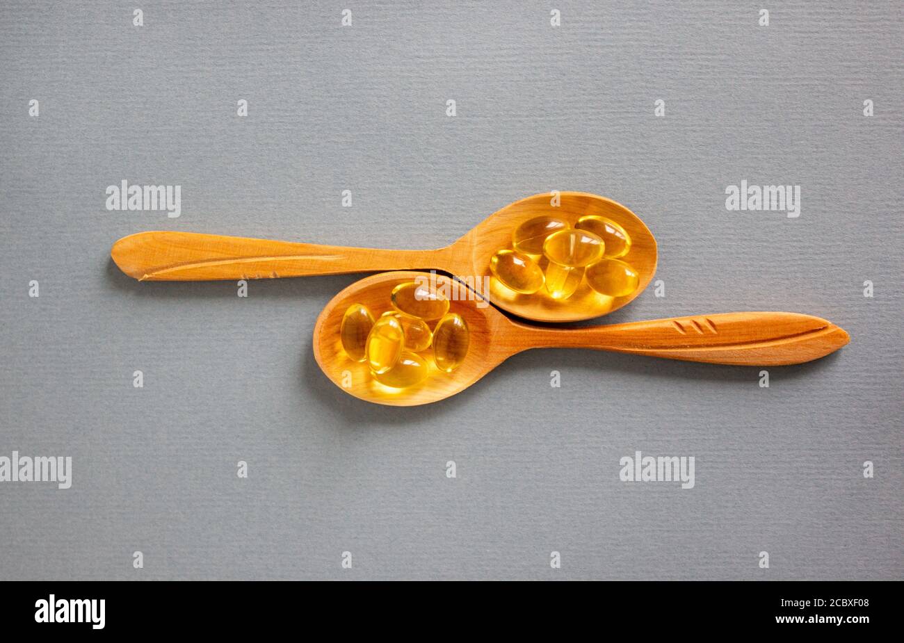 Medical concept. Wooden spoons with pills isolated on beautiful blue ...