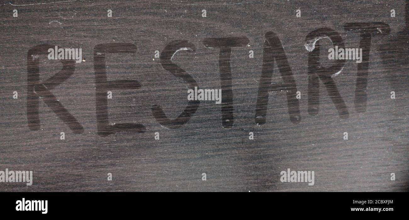 The word restart written with a finger on a dusty blackboard. Business ...