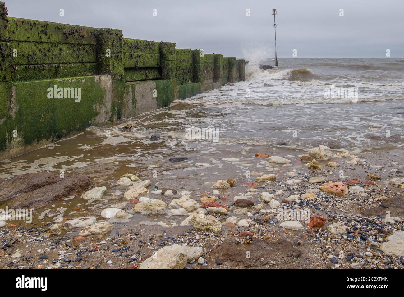 Waves from the incoming tide seen breaking on the groynes on Hunstanton ...