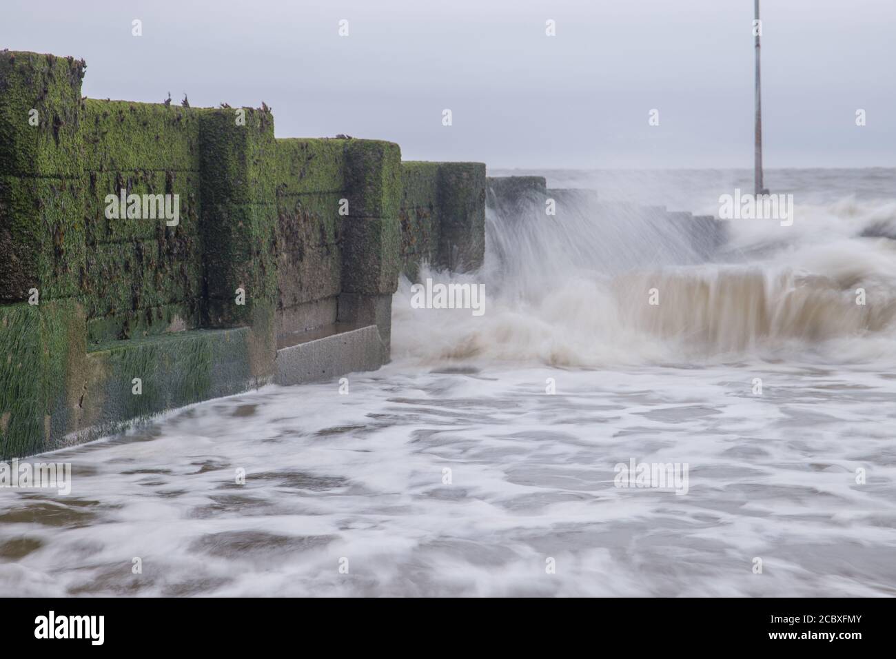Waves from the incoming tide seen breaking on the groynes on Hunstanton ...