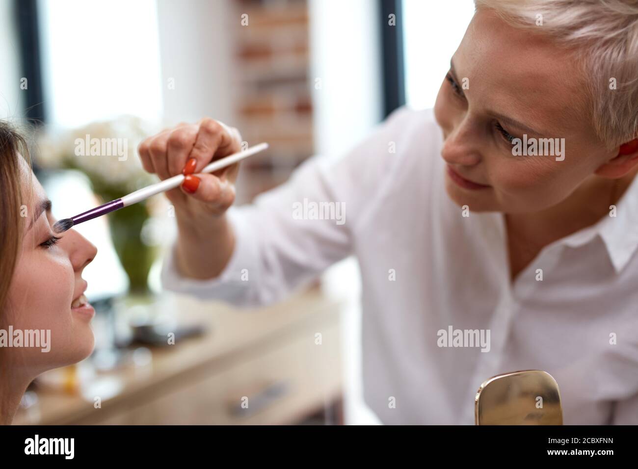 process of making makeup in beauty salon. visagiste working with brush ...