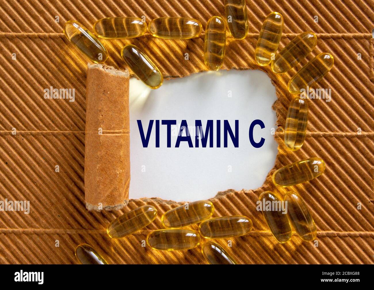 The text 'vitamin c' appearing behind torn brown paper. Yellow pills ...