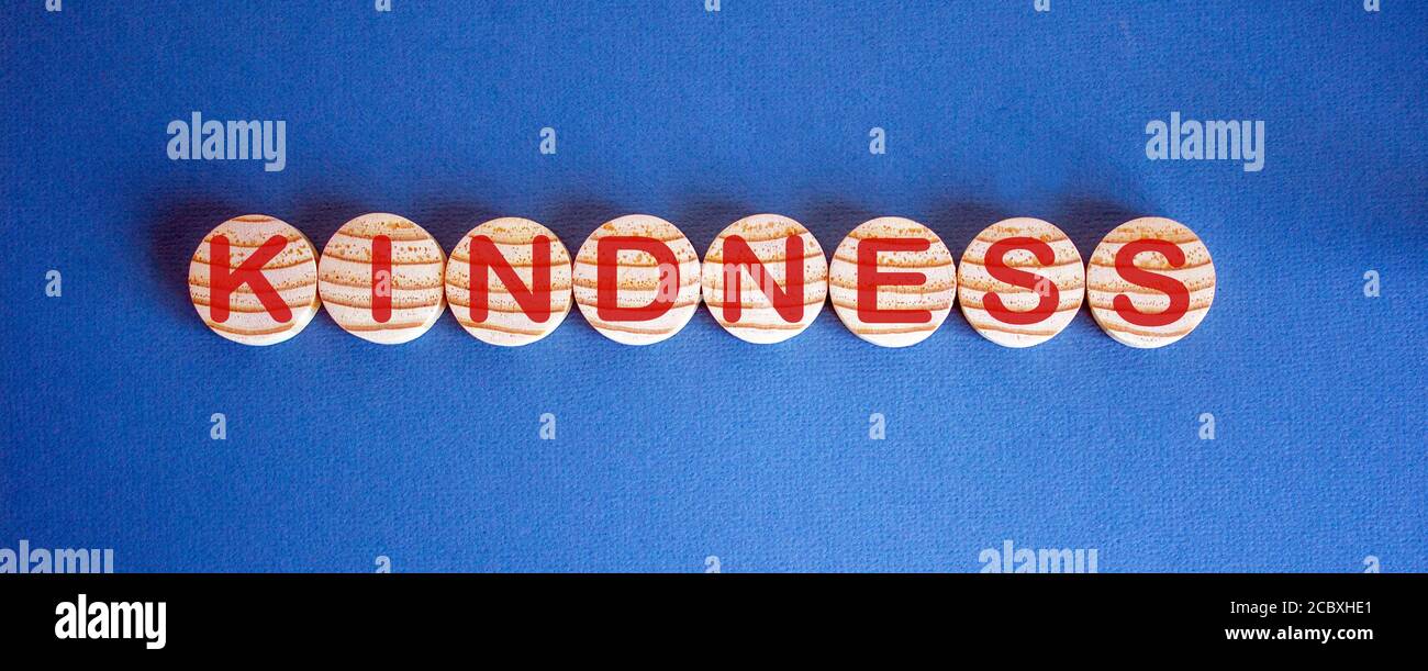 Wooden small circles with word kindness on blue background. Concept ...