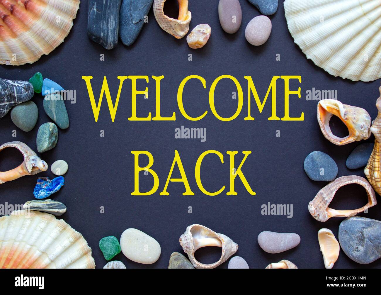 Word 'welcome back' on a beautiful black background. Sea stones and ...