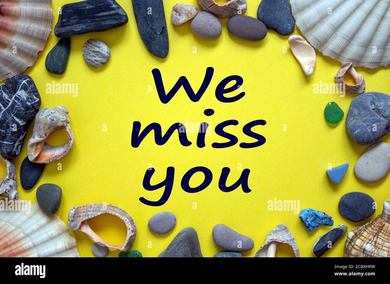 Word 'we miss you' on a beautiful yellow background. Sea stones and ...