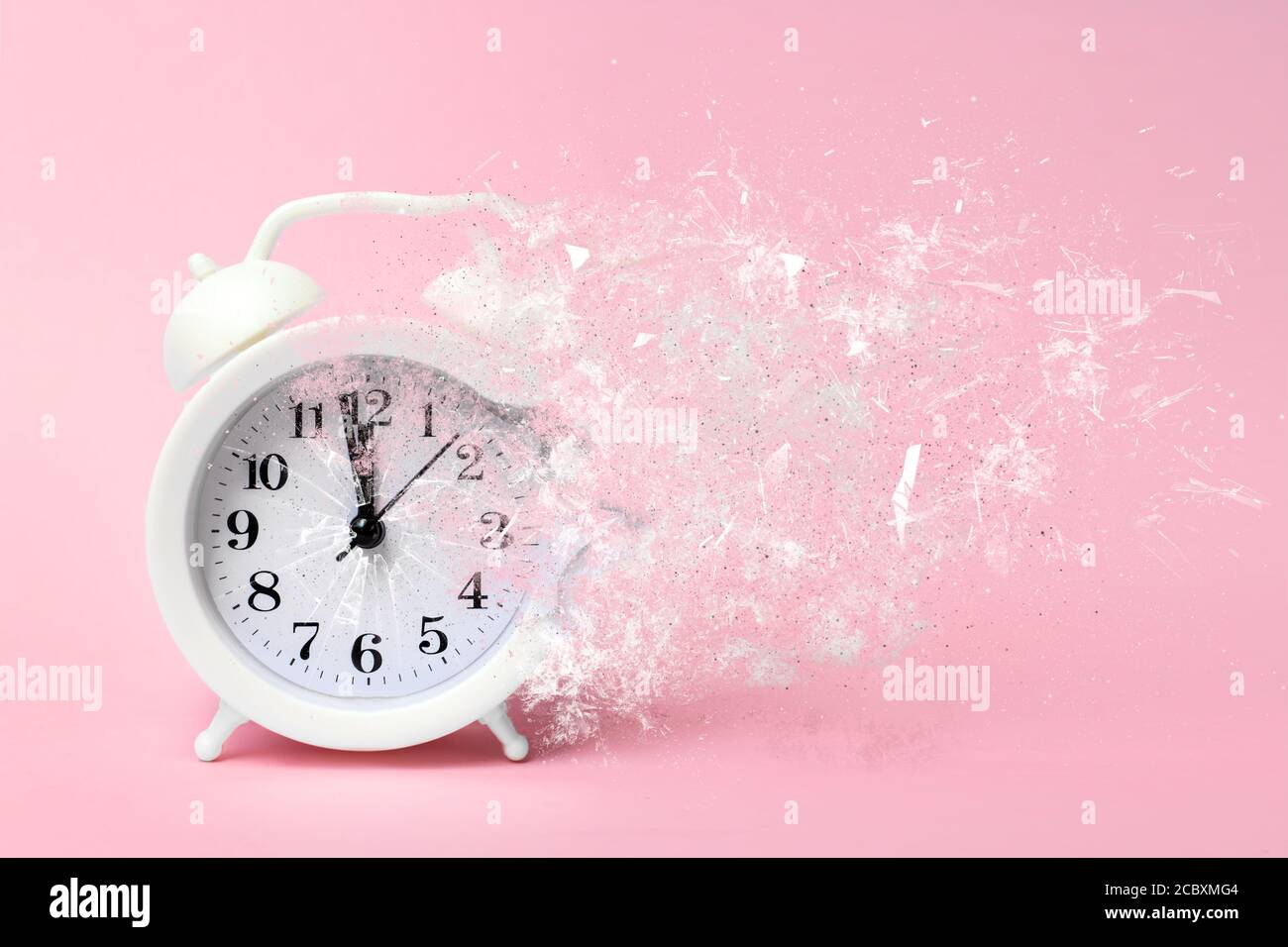 A hand holds alarm clock break down and dispersion to particle. A ...