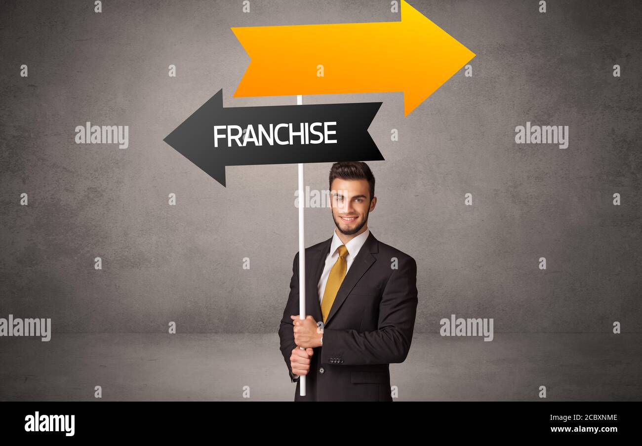 Young business person in casual holding road sign with FRANCHISE ...