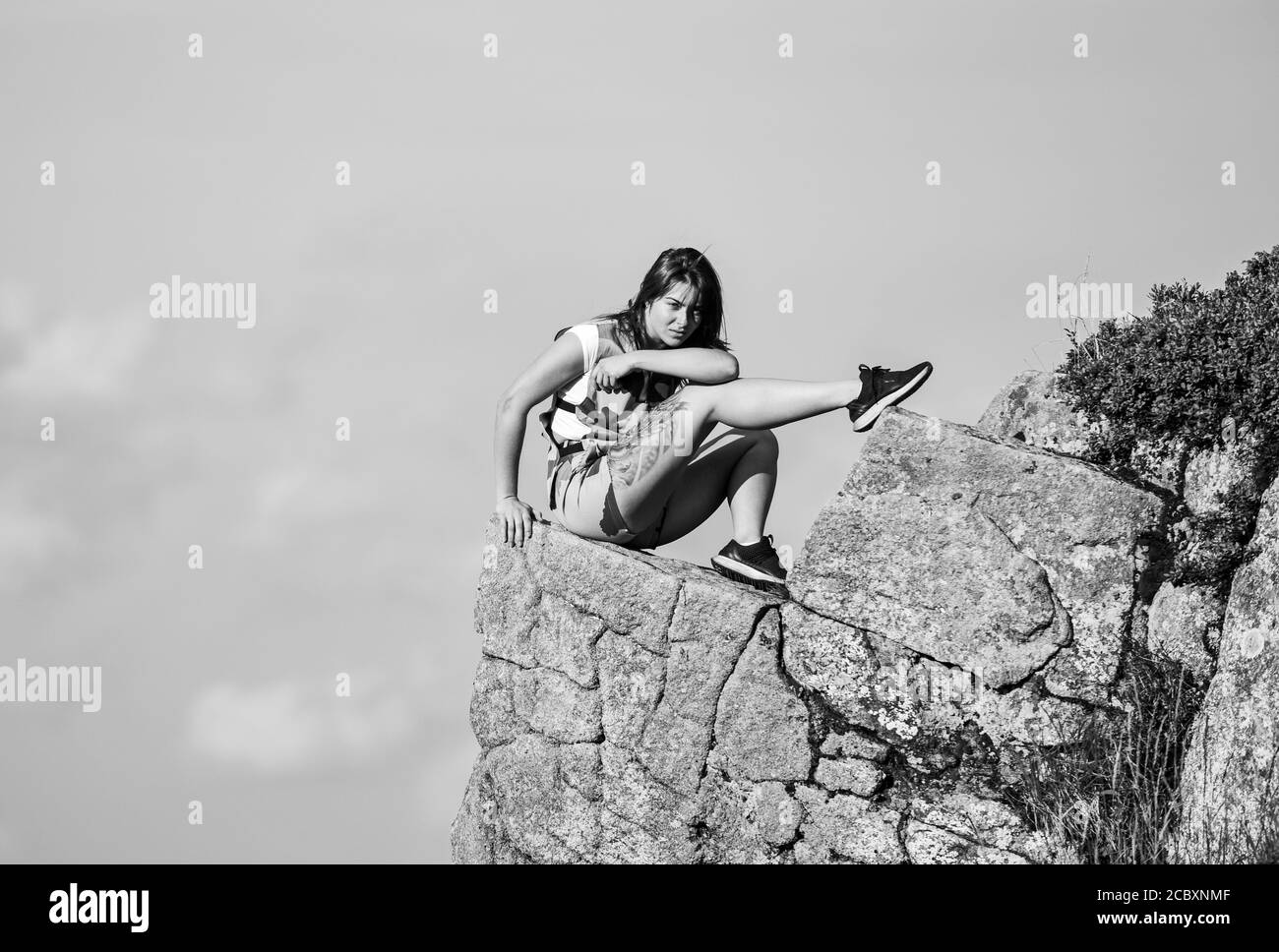 On edge of world. Woman sit on edge of cliff in high mountains blue sky ...