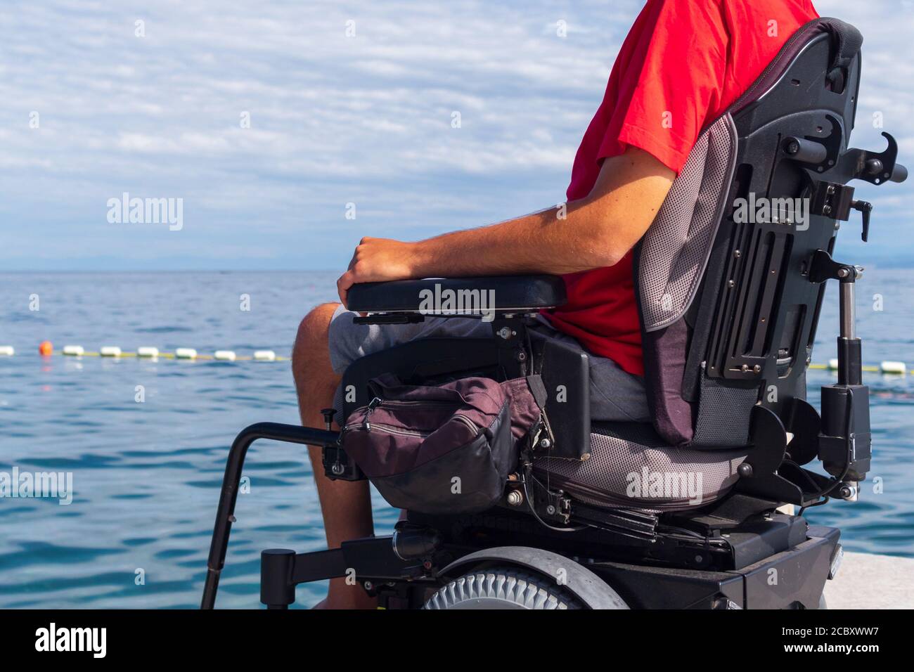 Man sitting in a wheelchair on the beach. Dangers of jumping into water ...