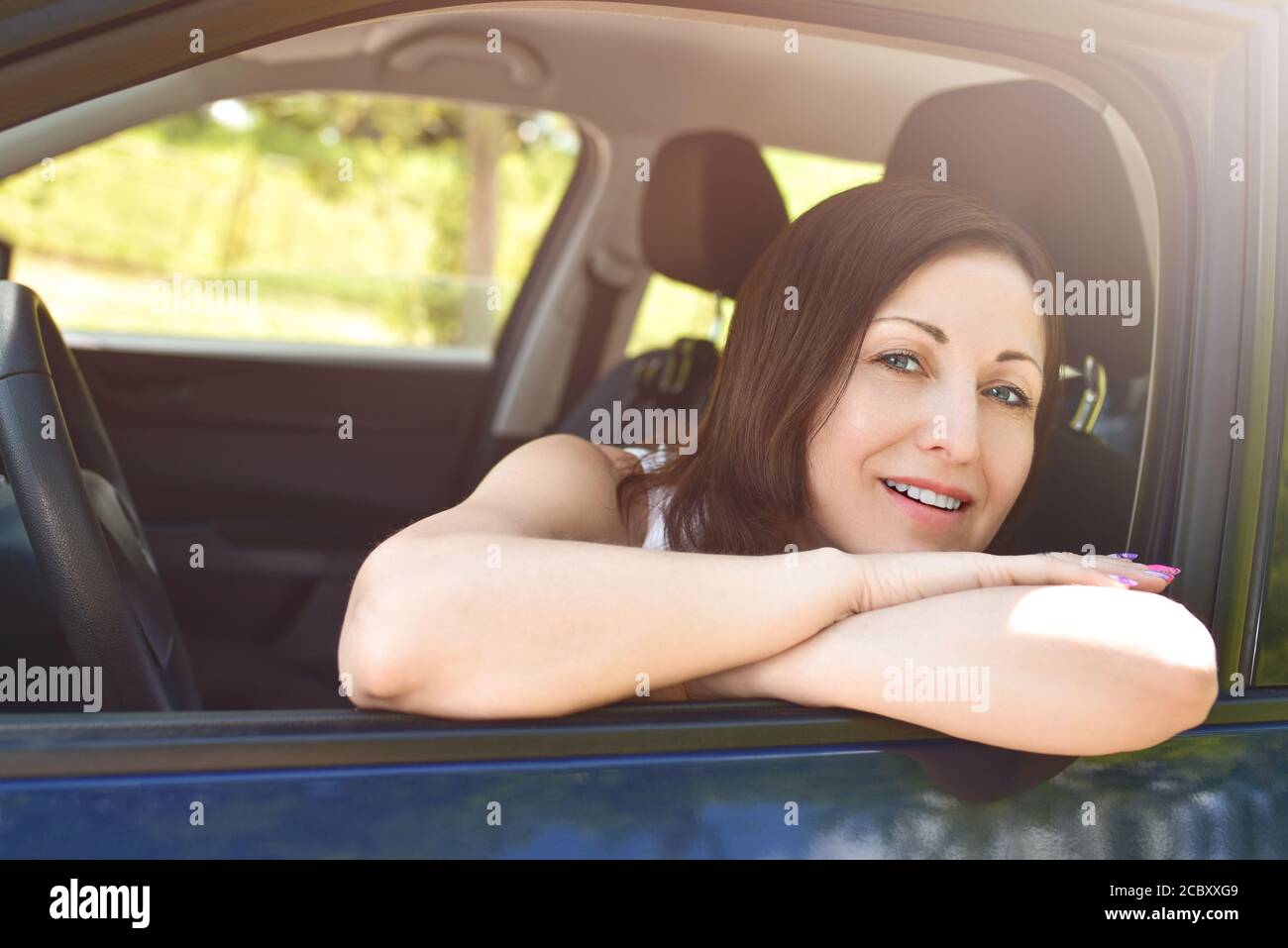 Smiling female driver looking out the car. a portrait of a smiling ...