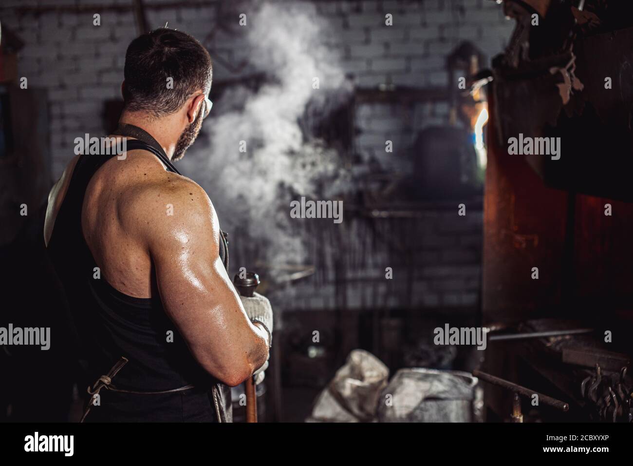 side view on unrecognizable forger bodybuilder, strong man, heating and ...