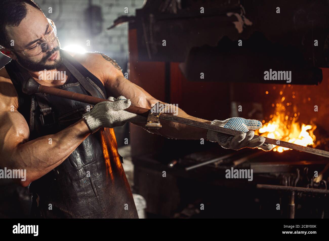 handsome blacksmith guy with muscular body, wearing gloves for safety ...