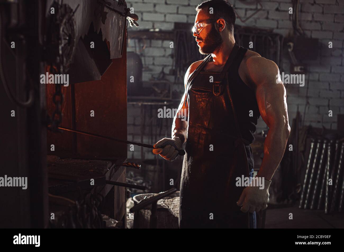 handsome blacksmith guy with muscular body, wearing gloves for safety ...
