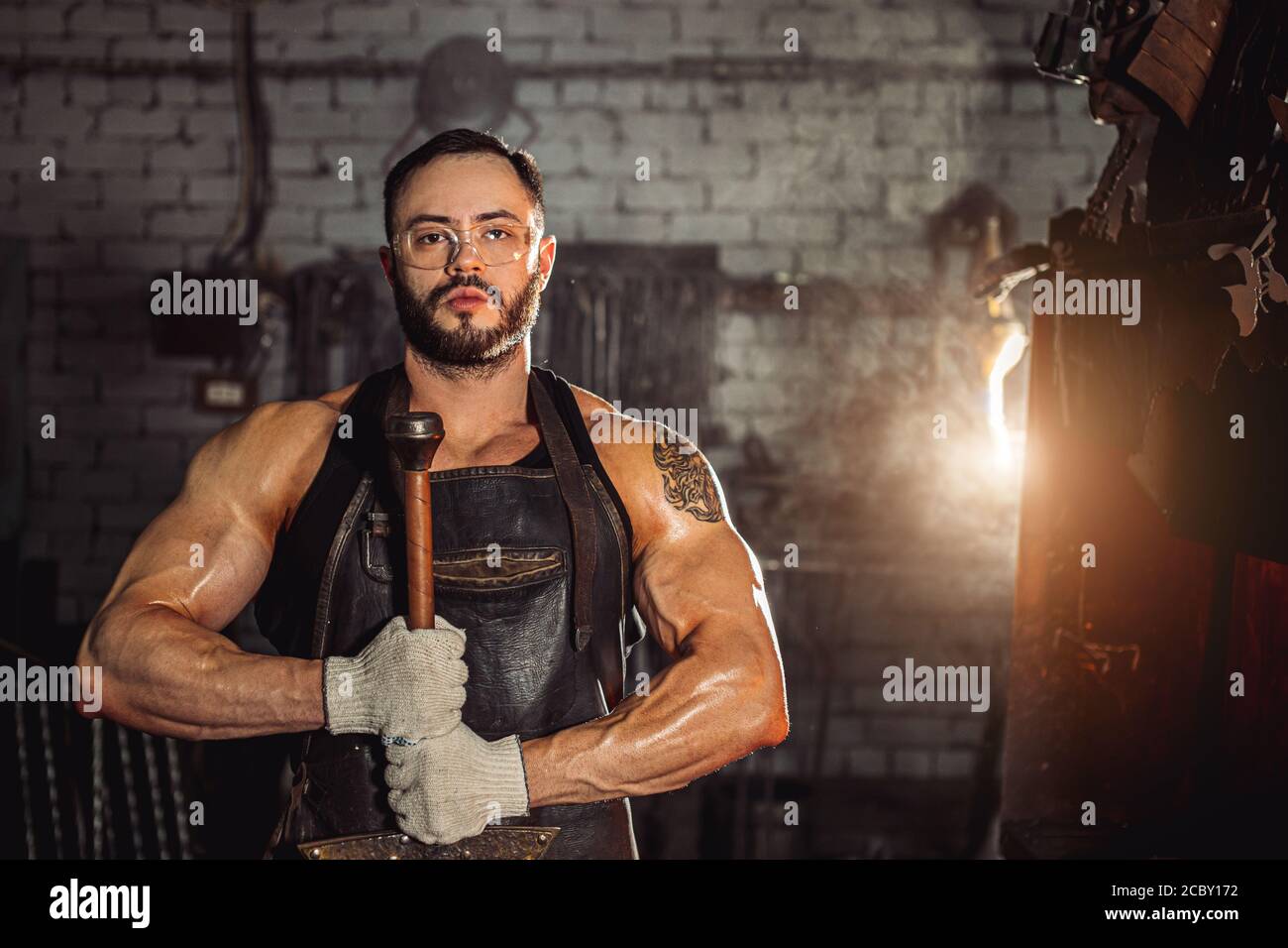 strong powerful muscular man engaged in forging, blacksmithing ...