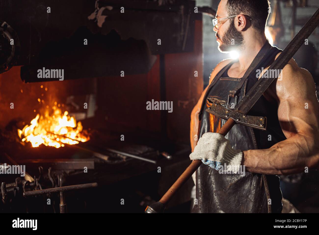 strong powerful muscular man engaged in forging, blacksmithing ...