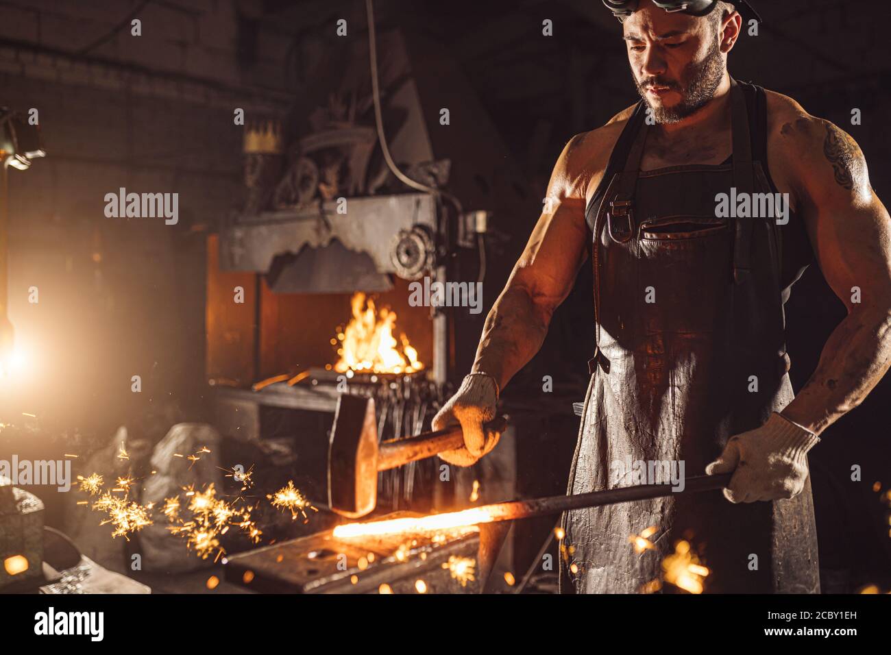 handsome forger having muscular body beat iron with hammer isolated in ...