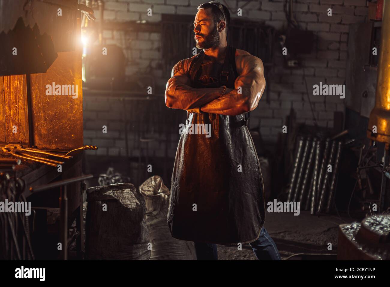 portrait of strong muscular blacksmith man wearing black apron, look ...