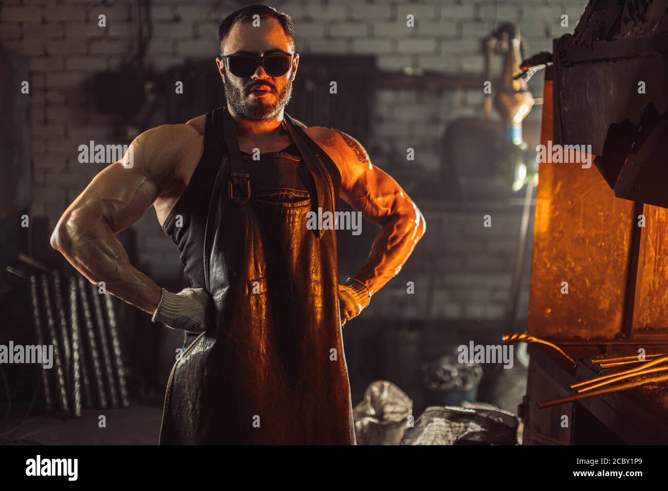 strong powerful muscular man engaged in forging, blacksmithing ...