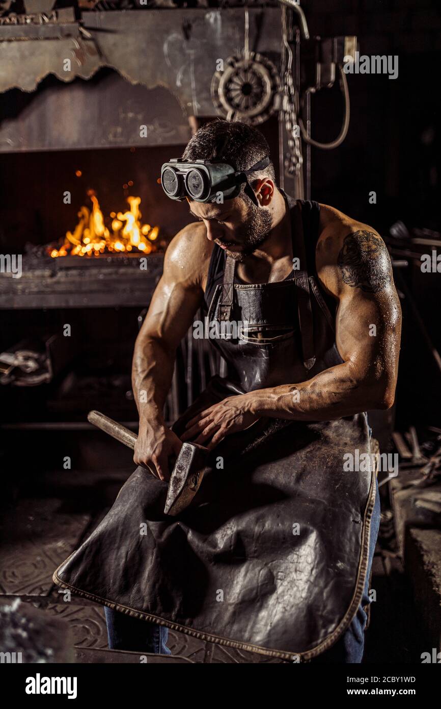 portrait of strong muscular handsome forger in leather uniform isolated ...