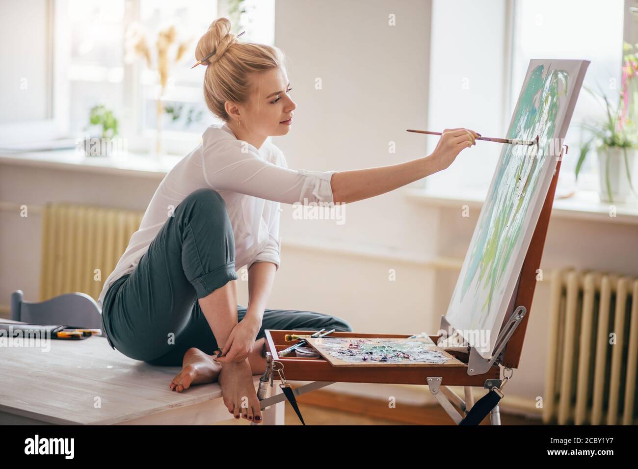 talented painter sitting with crossed legs and enjoying her pastime ...