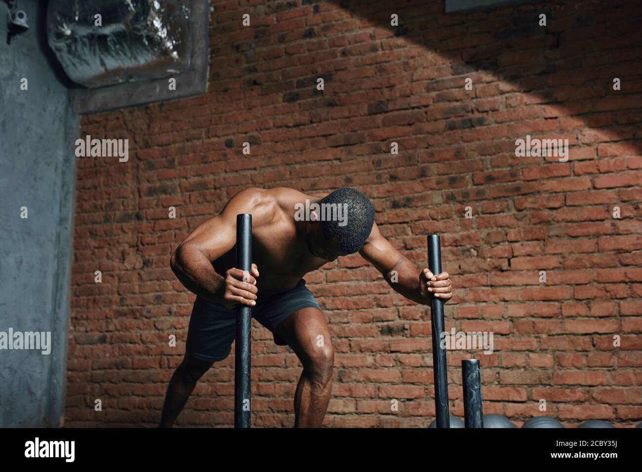 Dark-skinned male bodybuilder performing heavy weight Sled Push ...
