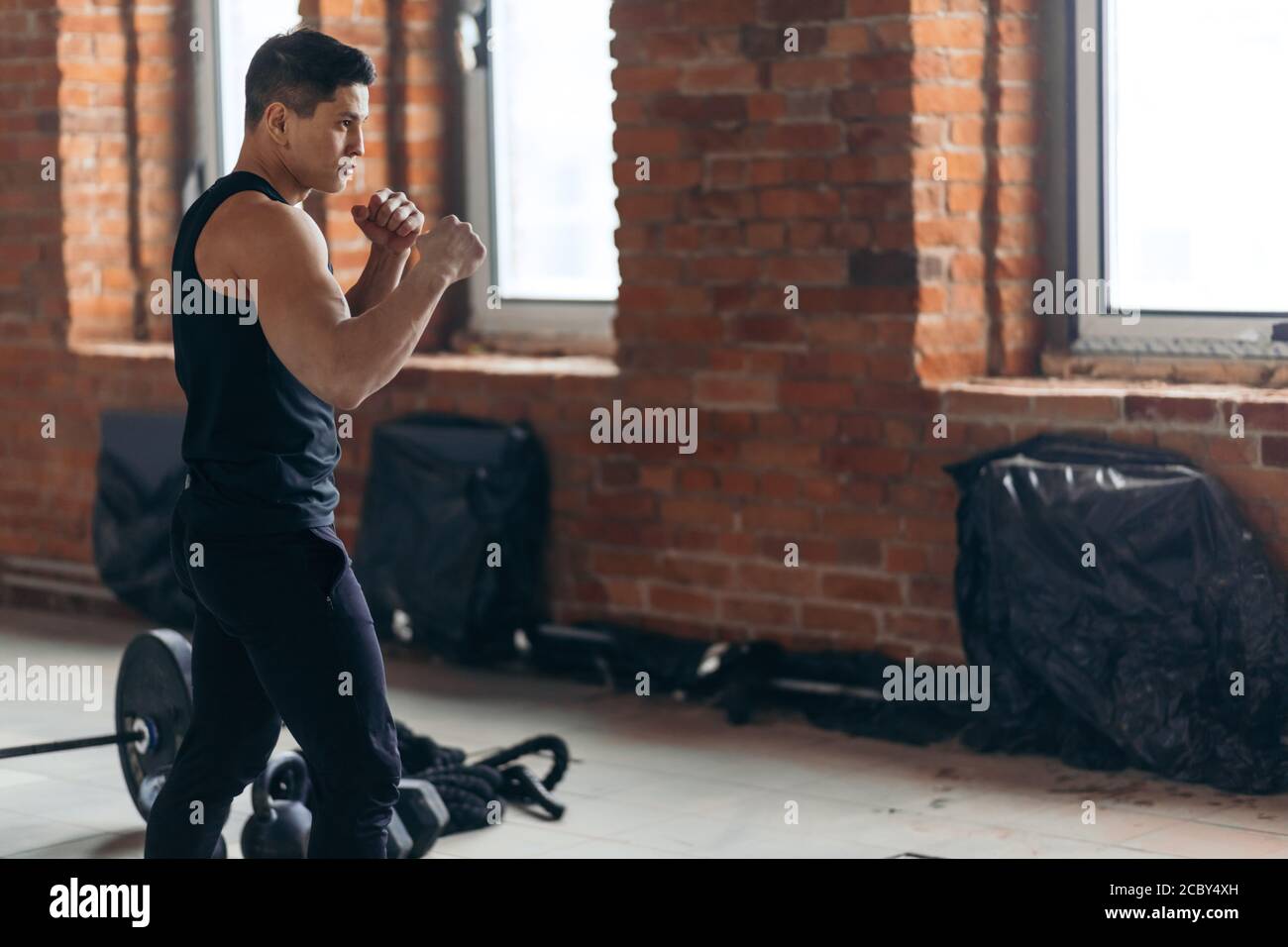 young motivated boxer with clenching fist standing in defense position ...