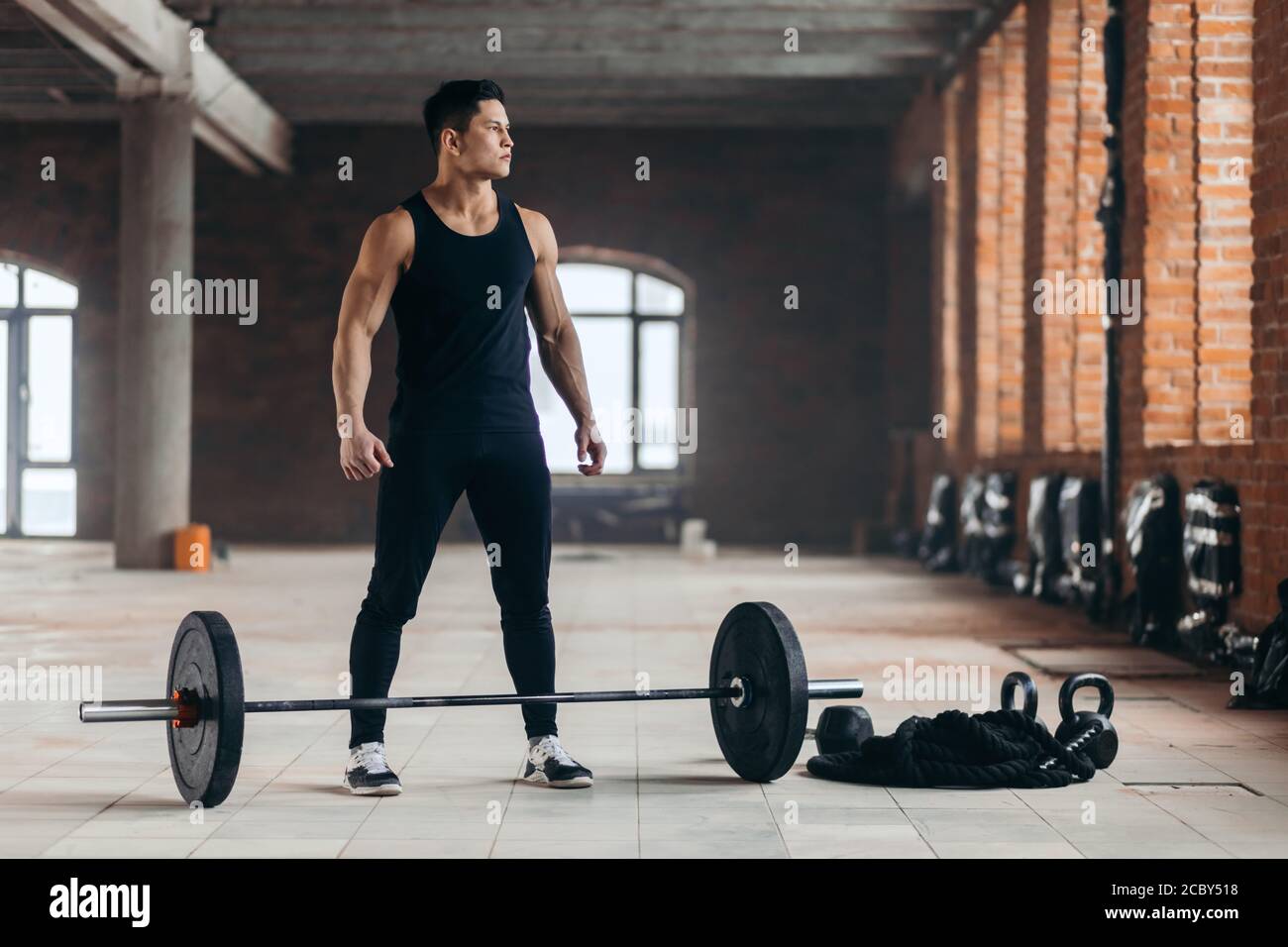 confident muscular fitness man standing at weight barbell before ...