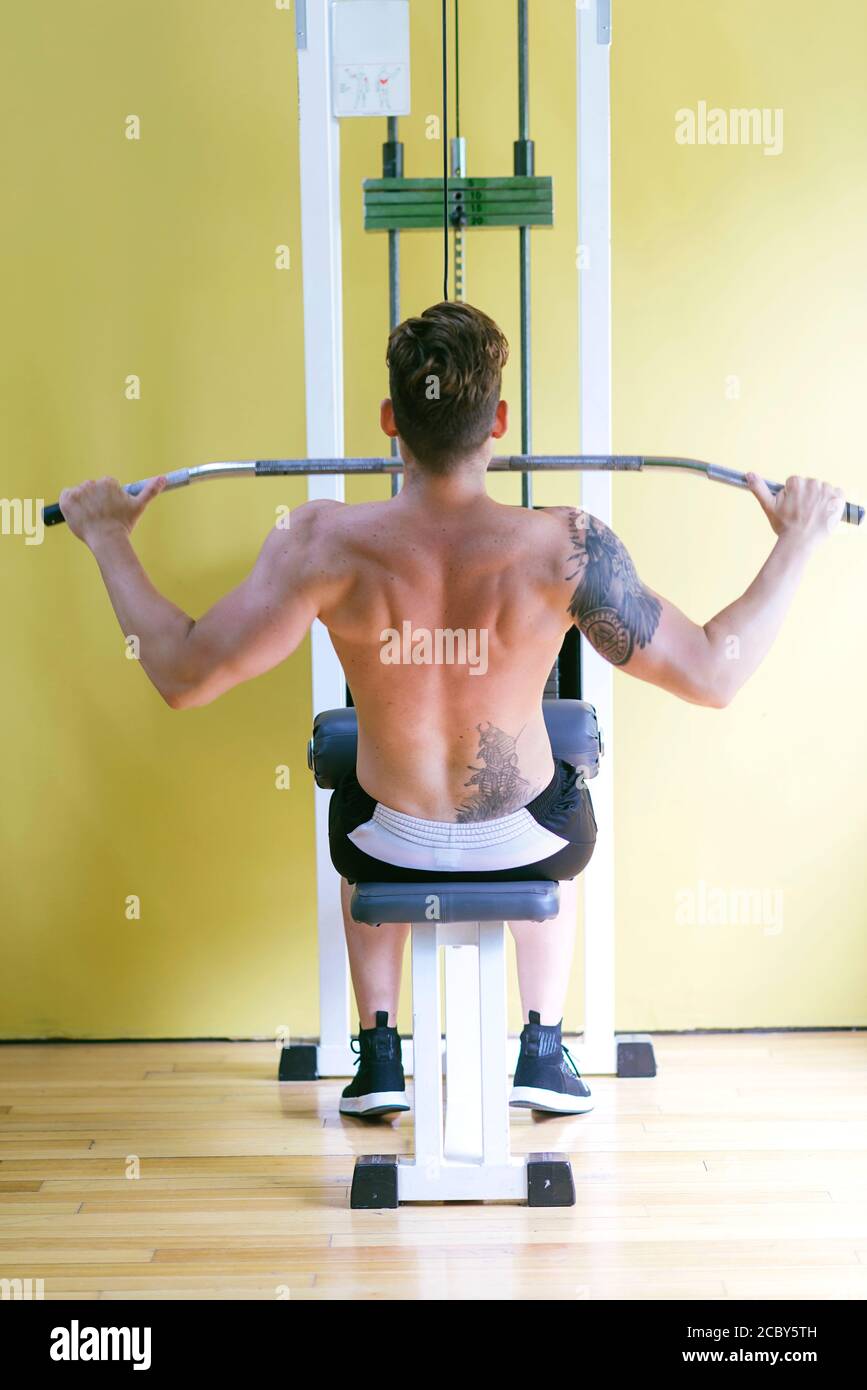 Fit man on lat pull down machine at the health club. Work out on Pull ...