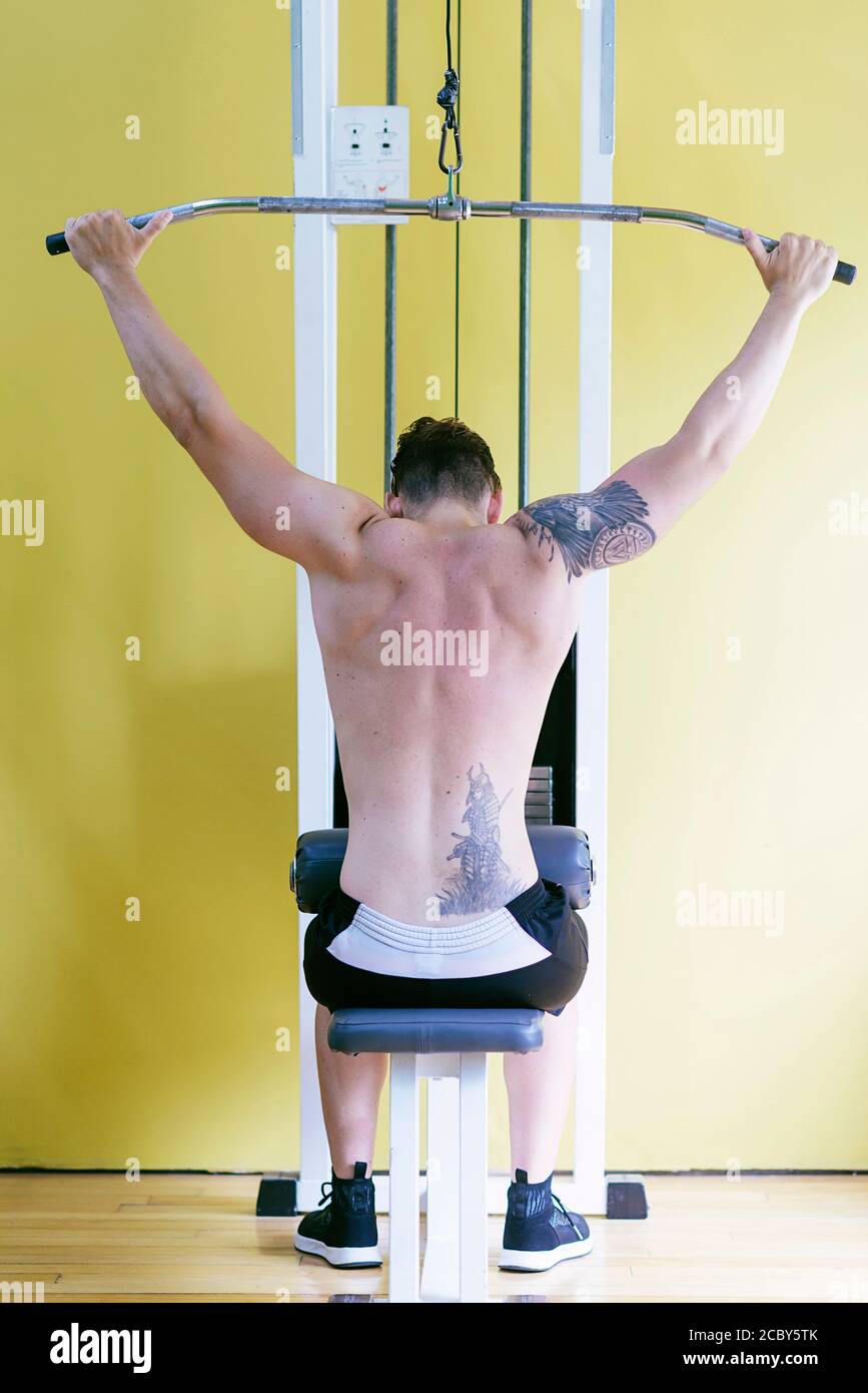 Fit man on lat pull down machine at the health club. Work out on Pull ...