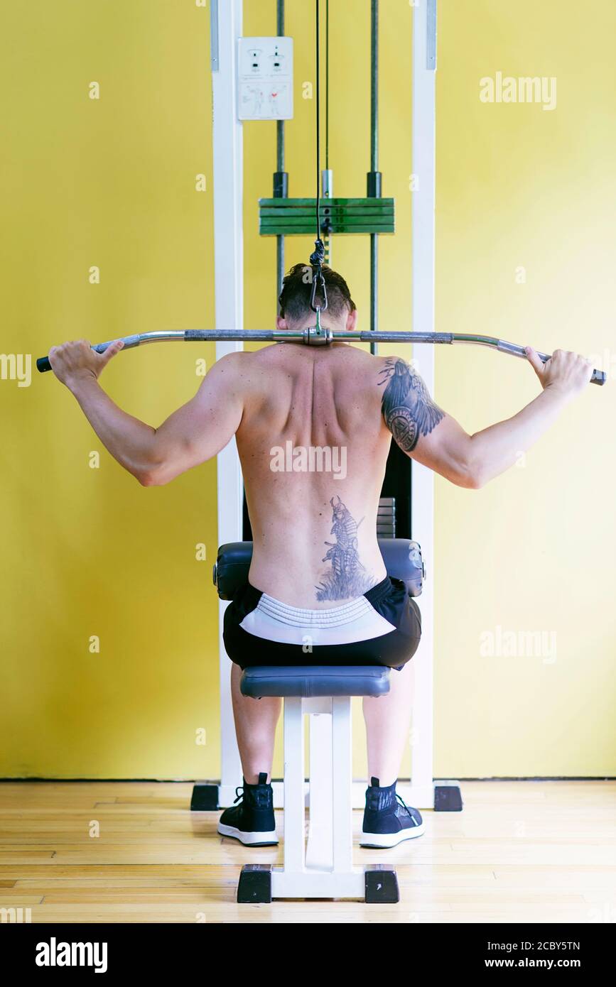 Fit man on lat pull down machine at the health club. Work out on Pull ...