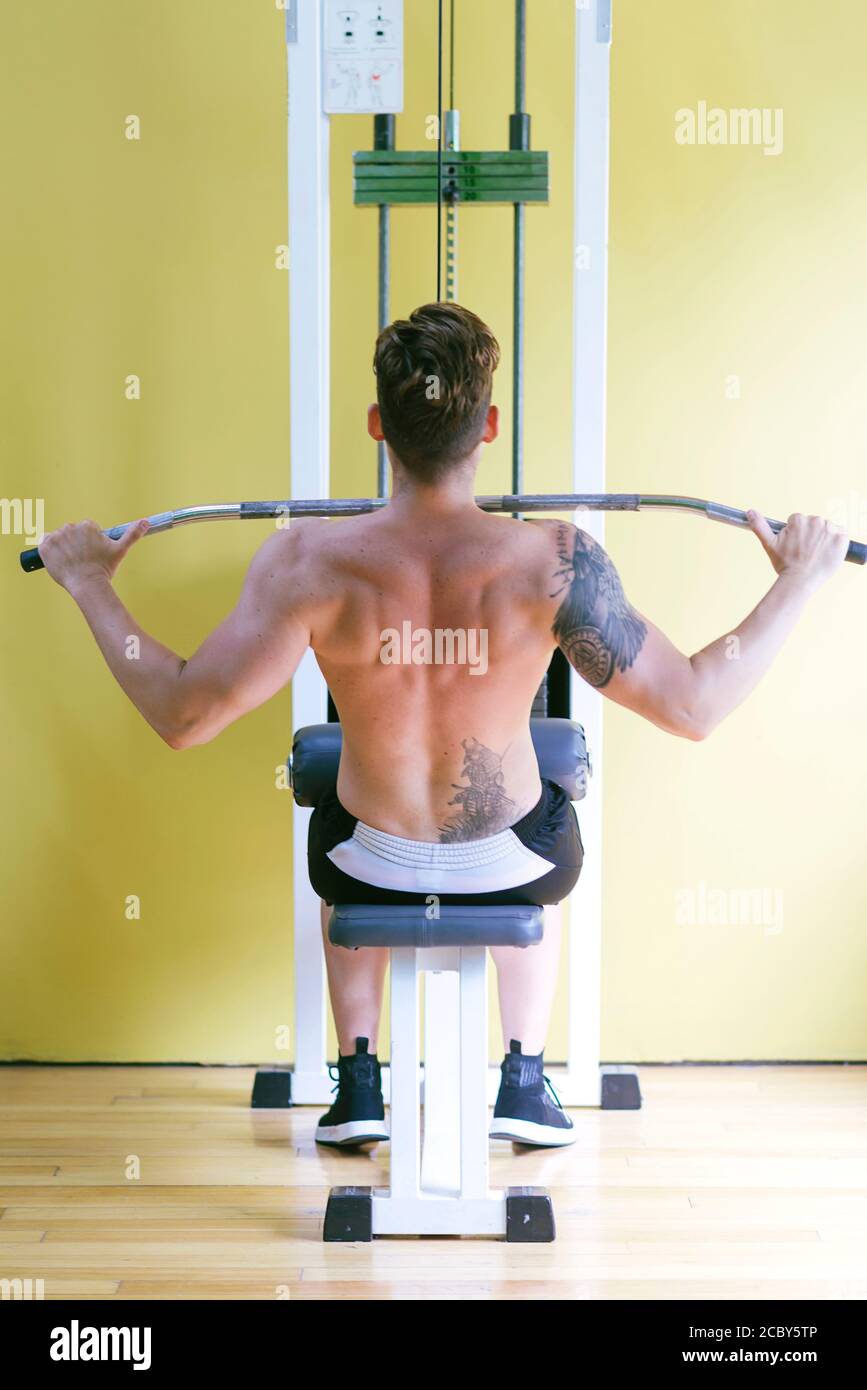 Fit man on lat pull down machine at the health club. Work out on Pull ...