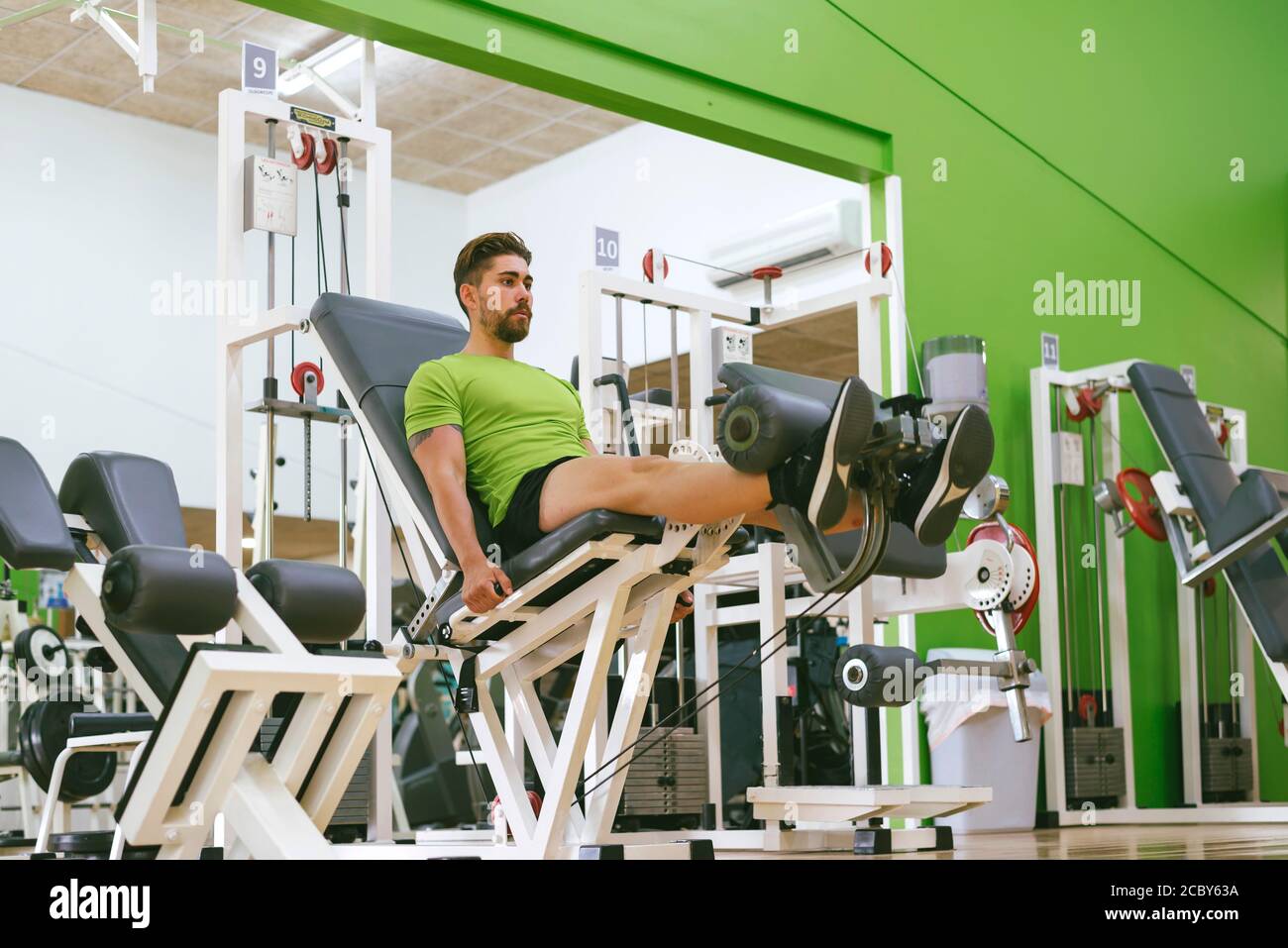 Young sportsman almost shouting when doing leg extension with heavy ...