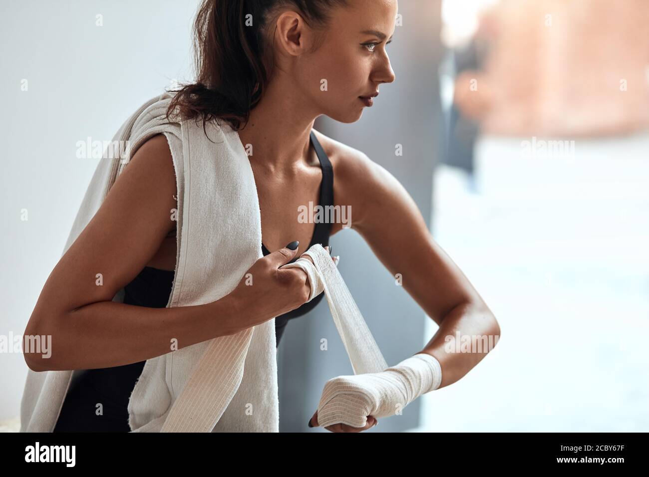Side view on fit female tying bandages on her hands before fitness ...