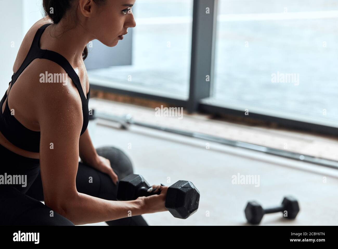Sporty muscular female in black sportswear training, pumping arms in ...