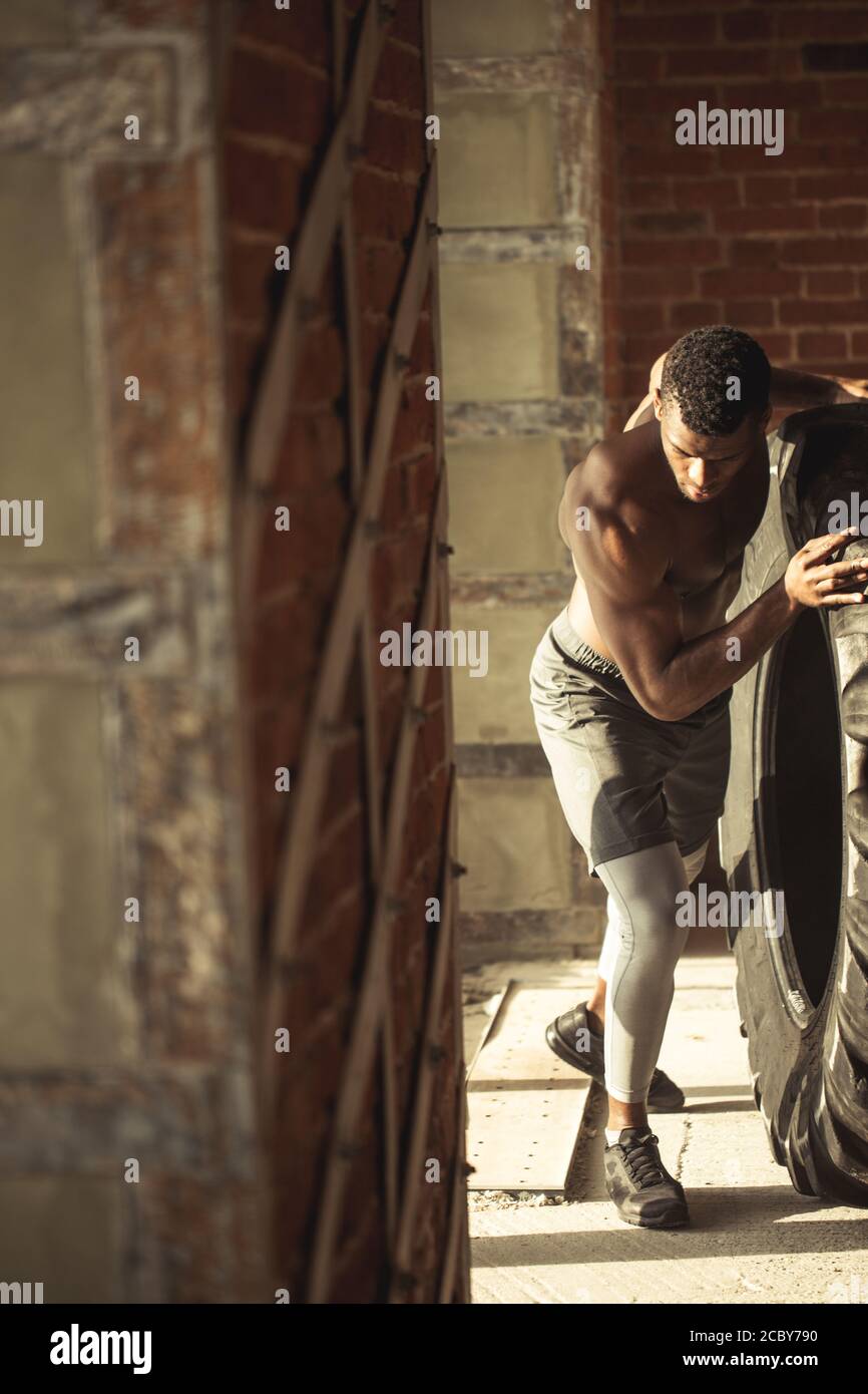 African american crossfit man makes an effort while pushing hard with ...