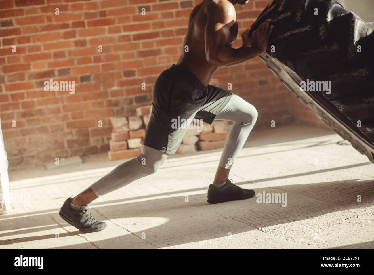 African american crossfit man makes an effort while pushing hard with ...