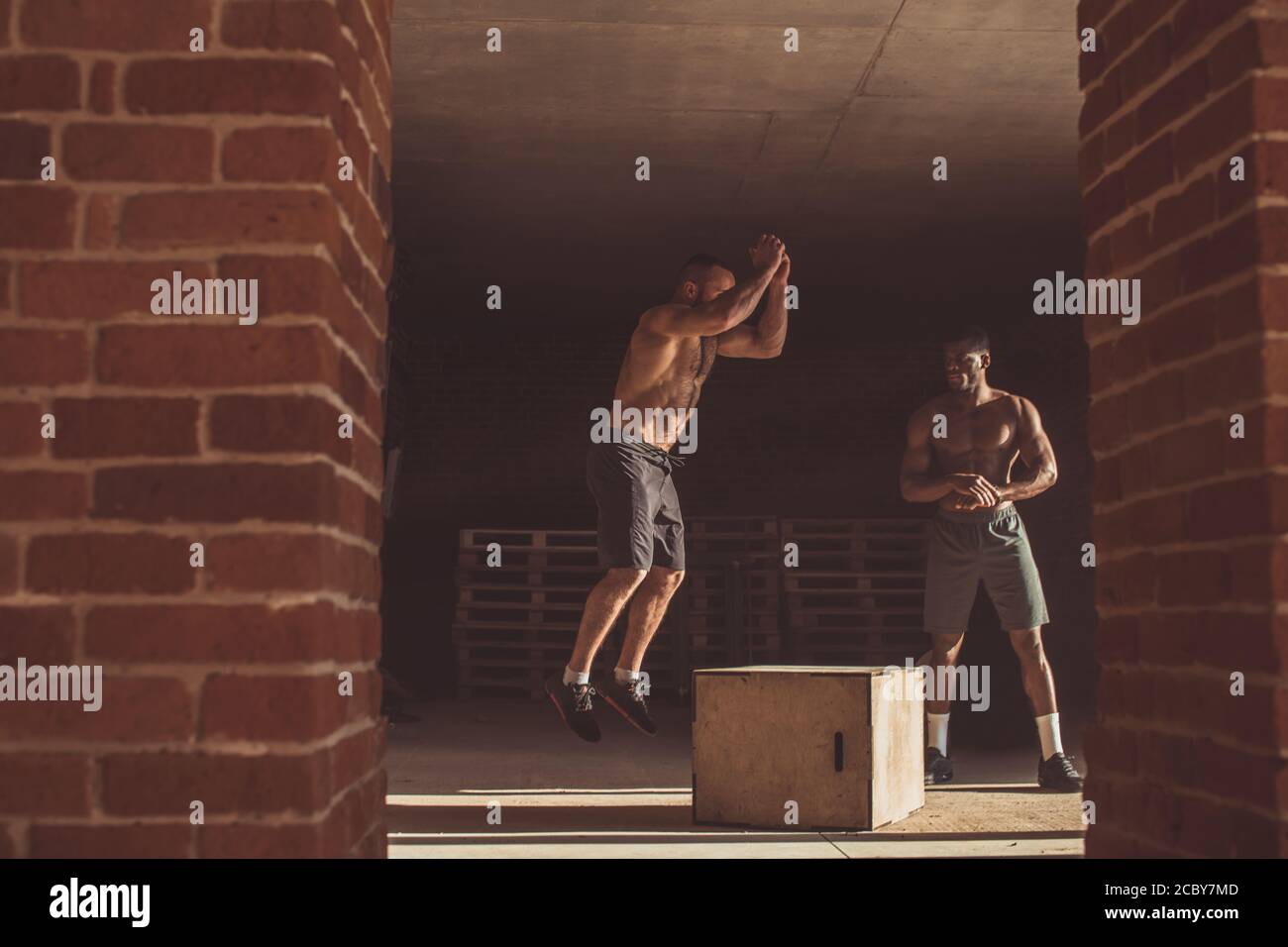 Two multi ethnic male sportsmen are jumping on plyo box. African ...